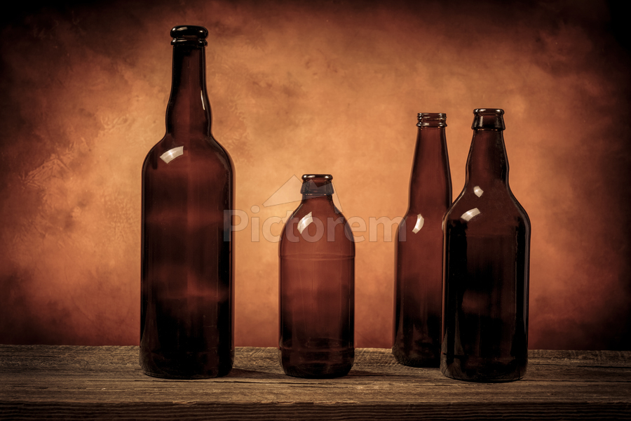 Four dark brown glass beer bottles on a barn wood table filter effect ...